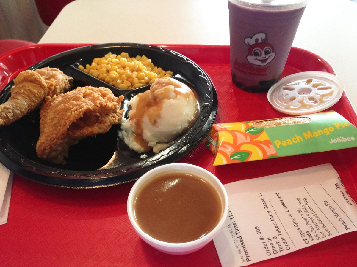 A plate with two pieces of fried chicken, two sides, a smoothie and a ...
